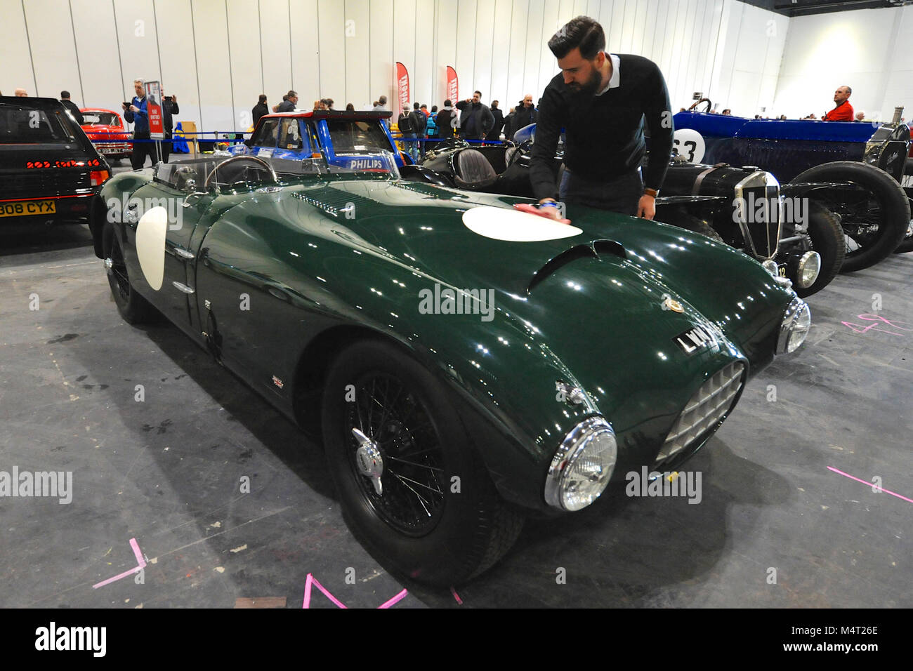 A man polishing a 1955 Jaguar XK140 Special racing car on display at ...