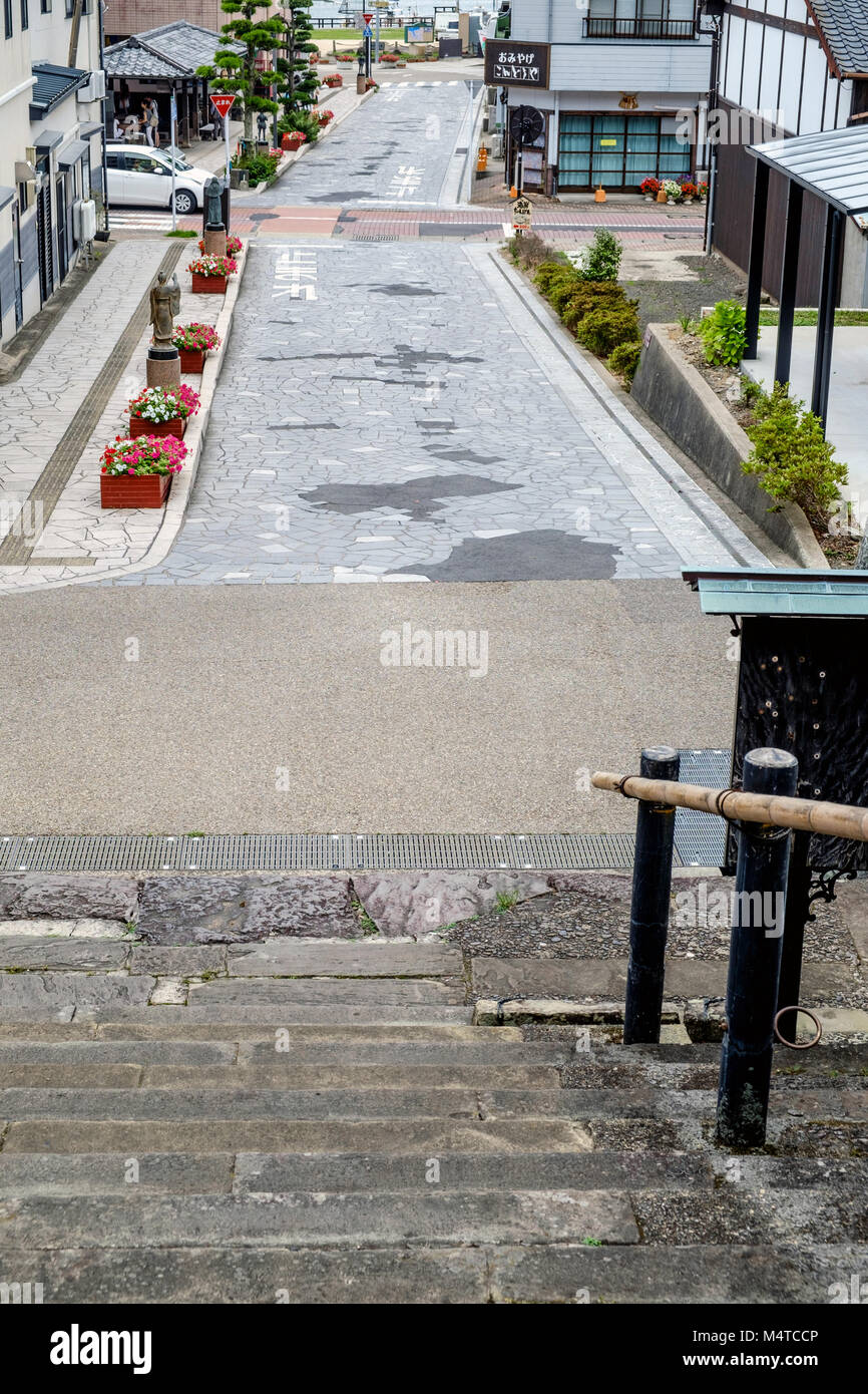 Steps leading down to street with shops on both sides. Flower boxes ...