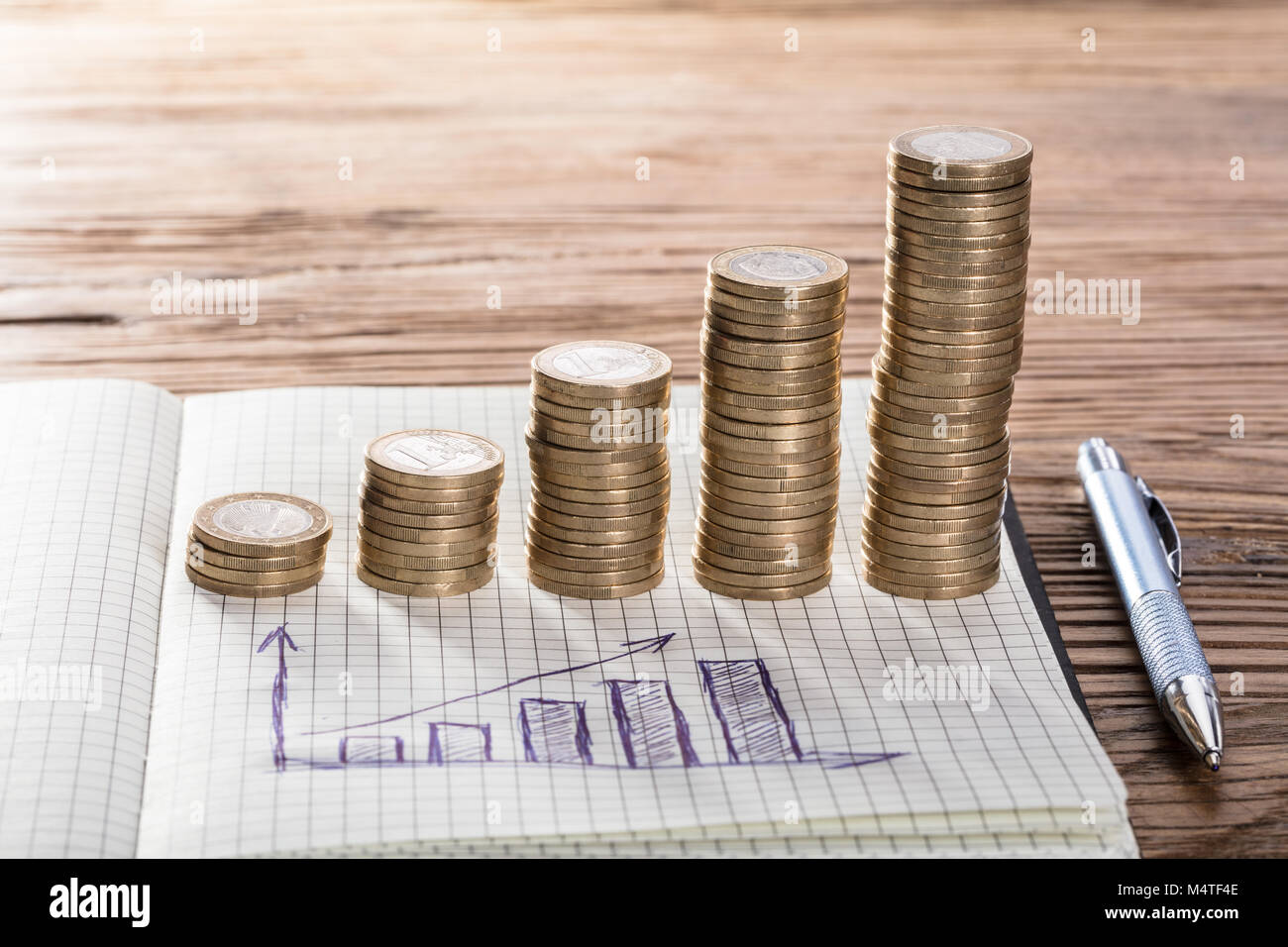 Increasing Coin Stacks With Graph On Notebook Over The Wooden Table ...