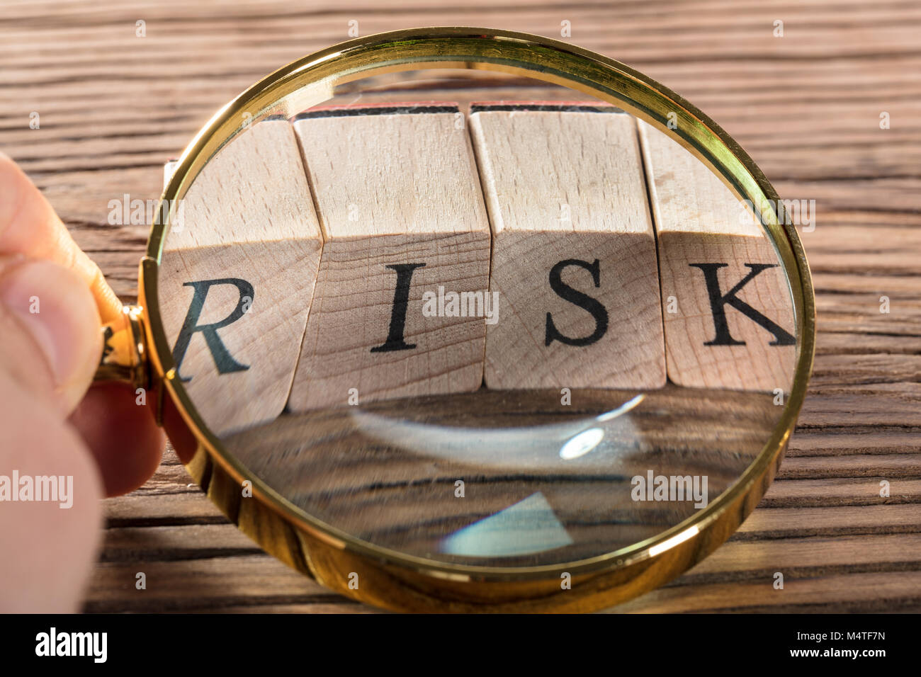 A Person Examining Risk Blocks Through Magnifying Glass On Wooden Table ...