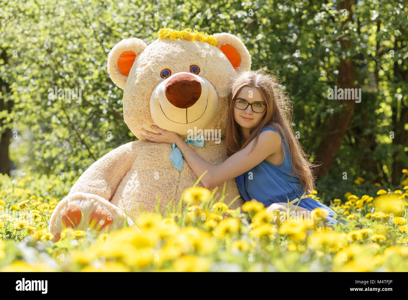 girl with teddy bear sitting on dandelion meadow Stock Photo - Alamy