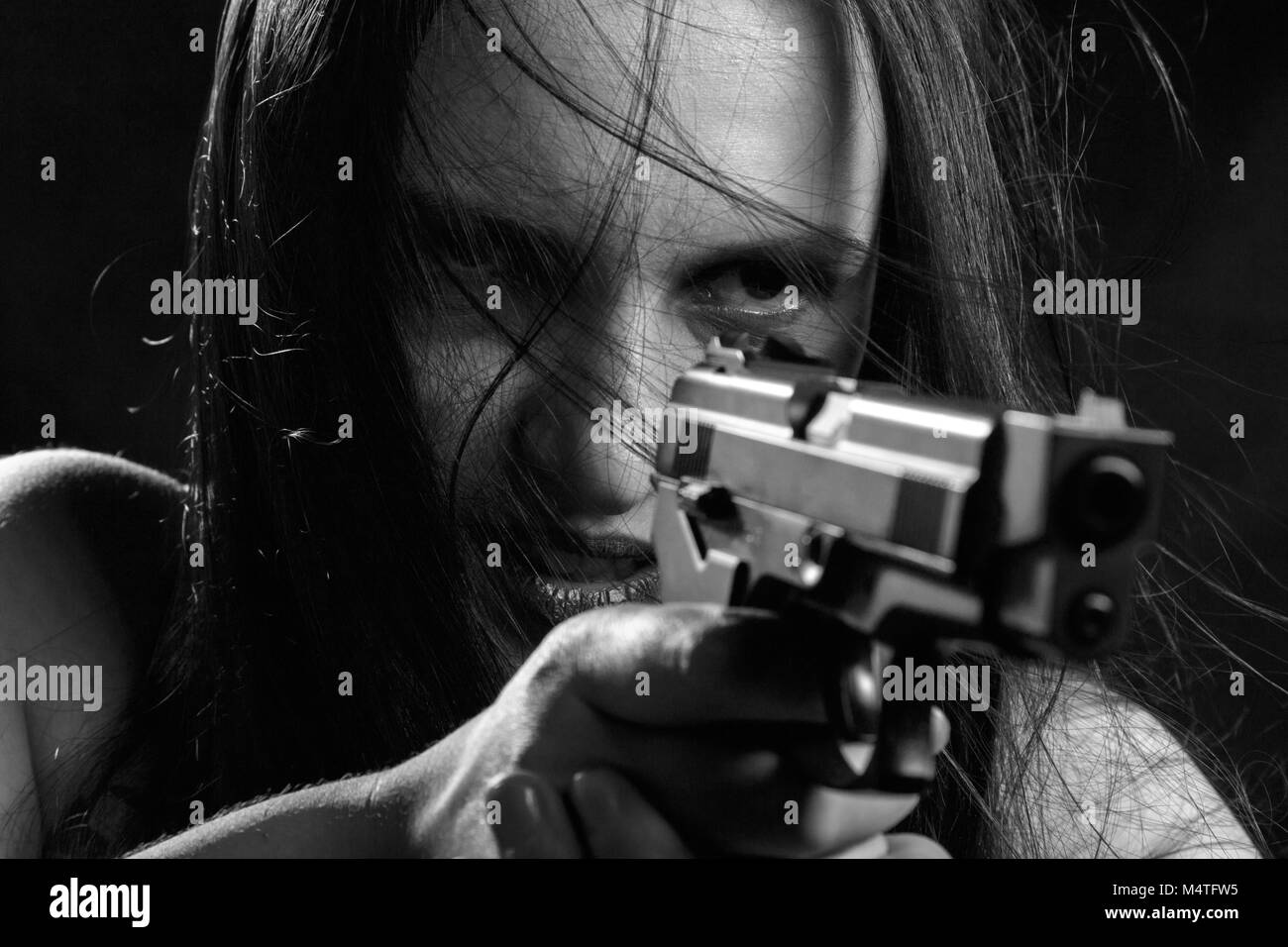 angry young woman with gun aiming on red background, monochrome Stock ...
