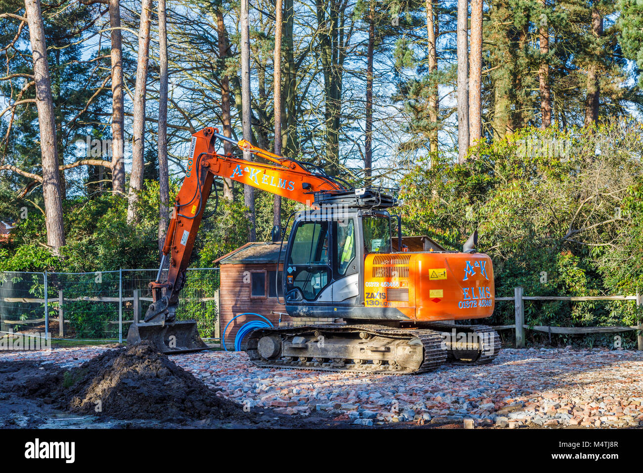 Large orange mechanical digger standing on a platform of hard core ...