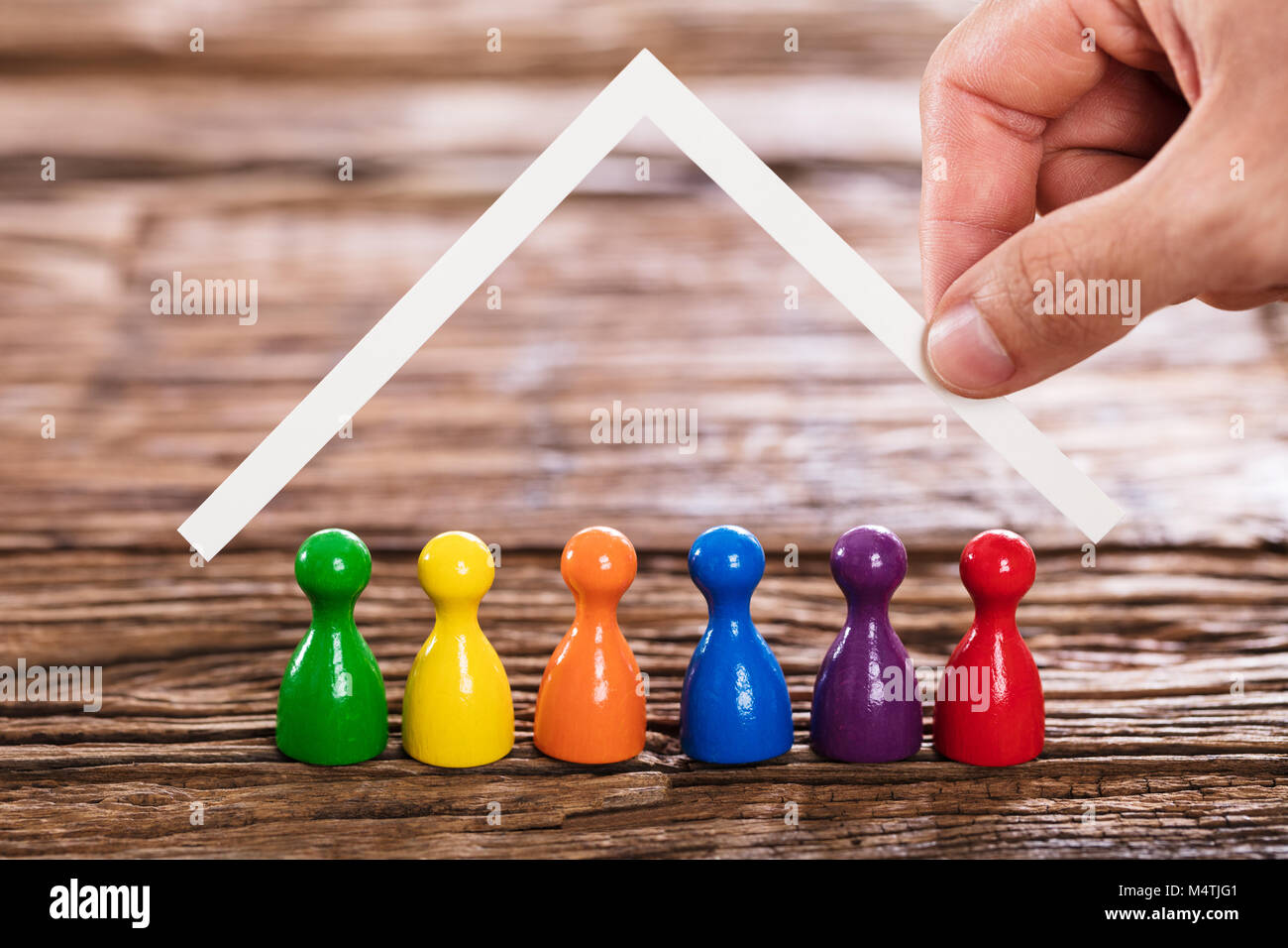 Close-up Of A Person Hand And Multi Colored Person Under Home Roof On ...