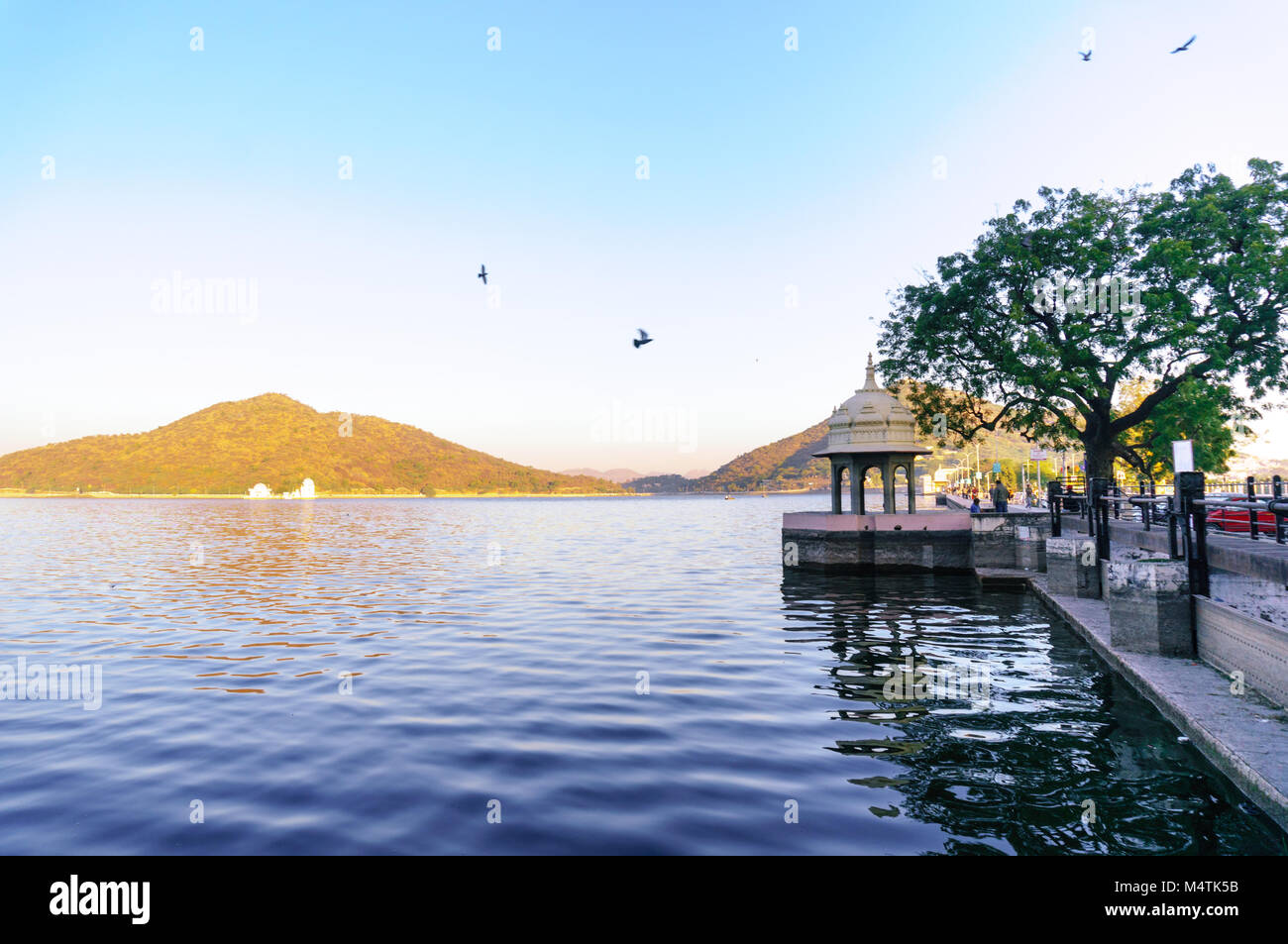 Morning shots of the fateh sagar lake with blue water, a walkway and ...