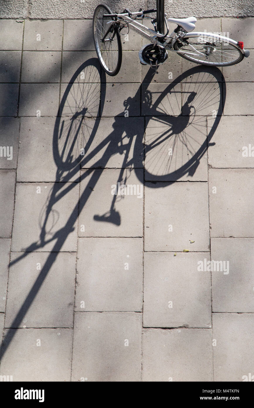 An unusual view of a parked bike with long shadows on the pavement ...