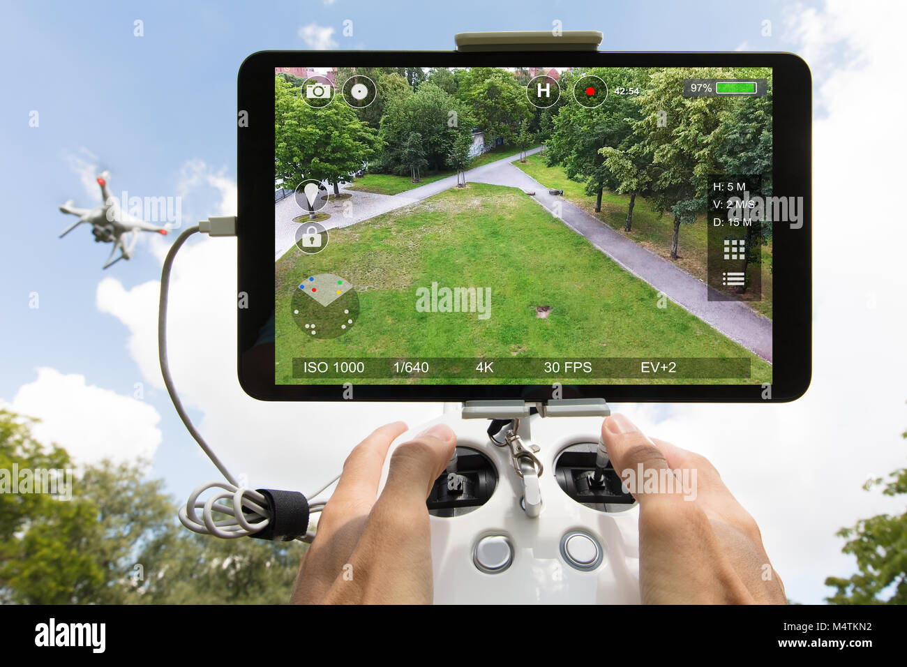 Cropped image of hands controlling drone filming park seen on digital ...