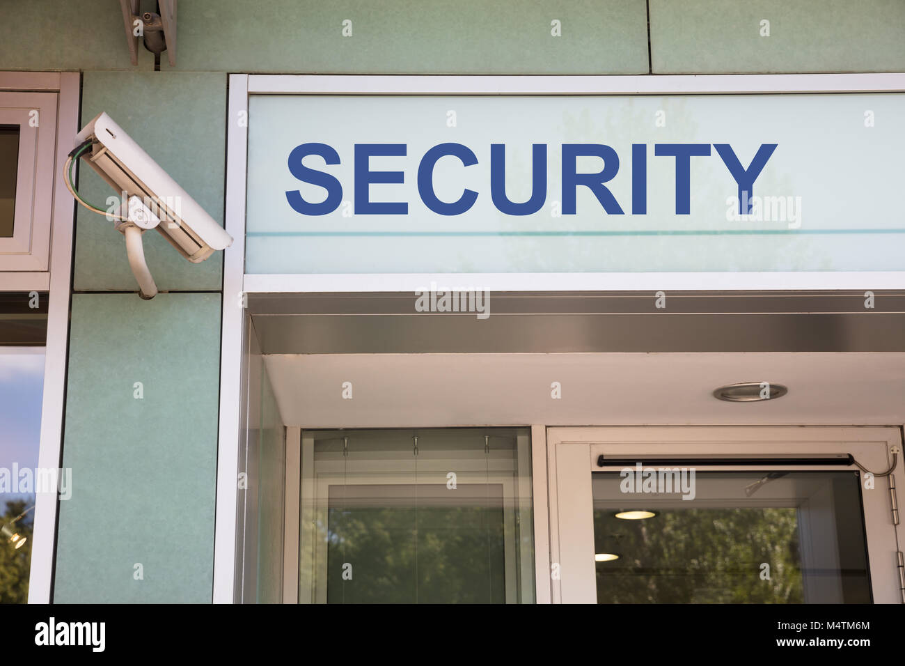 Security camera and sign at entrance of modern office building in city ...