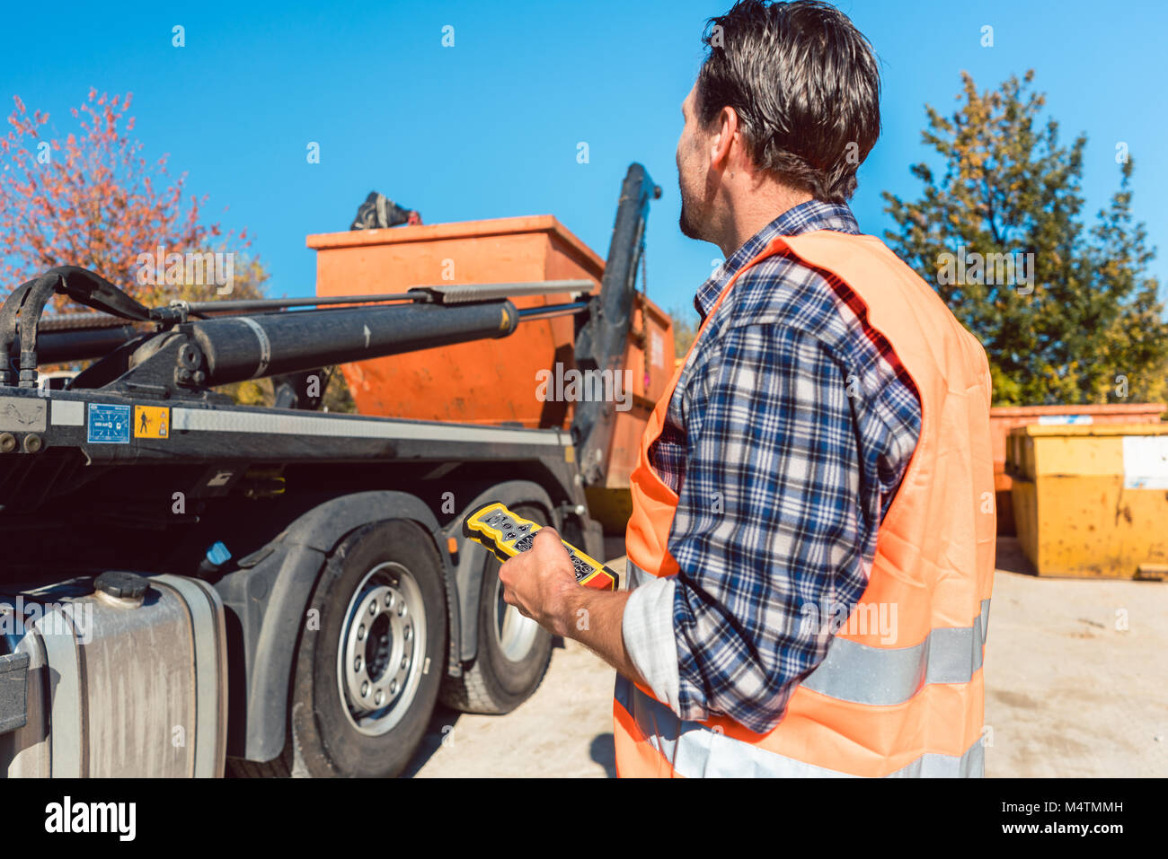 Worker on construction site unloading container for waste from truck ...