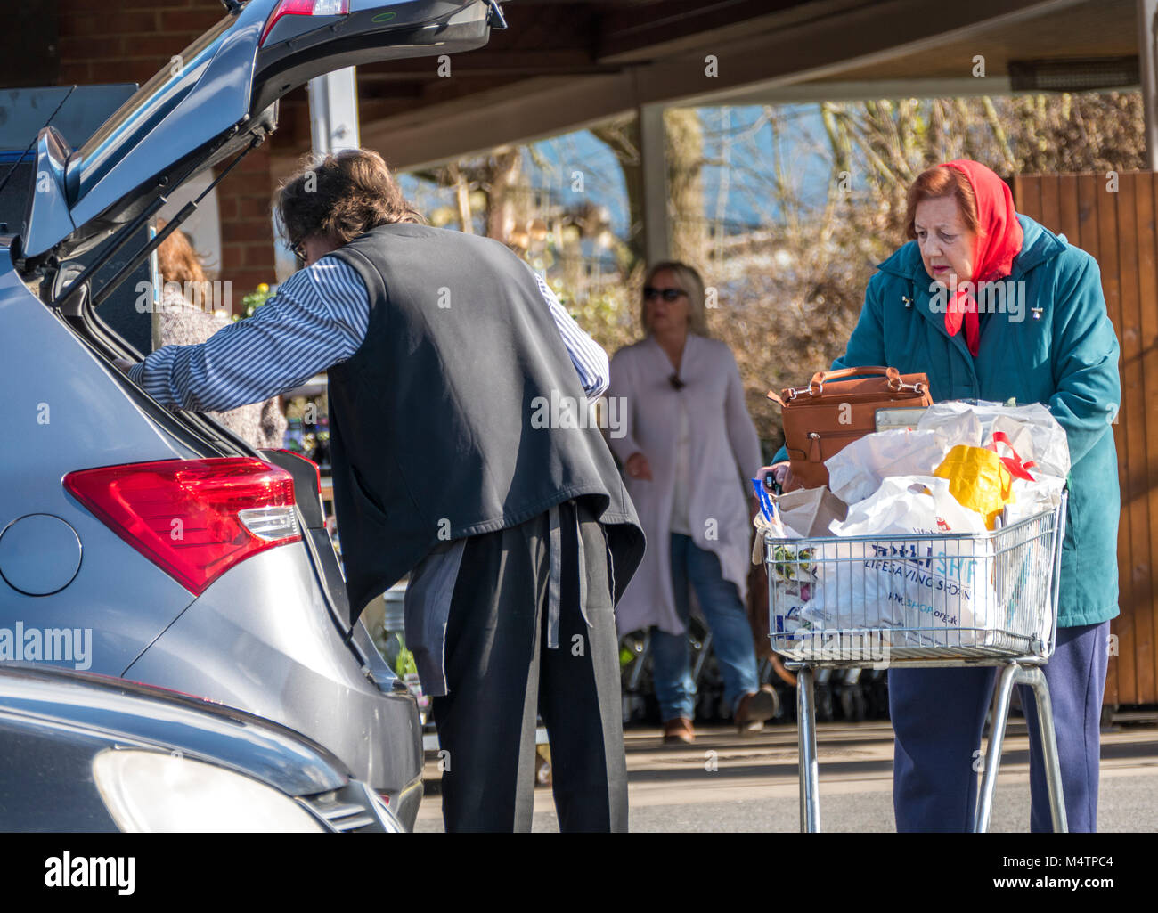 Male Waitrose supermarket employee, helping an old / elderly woman with ...