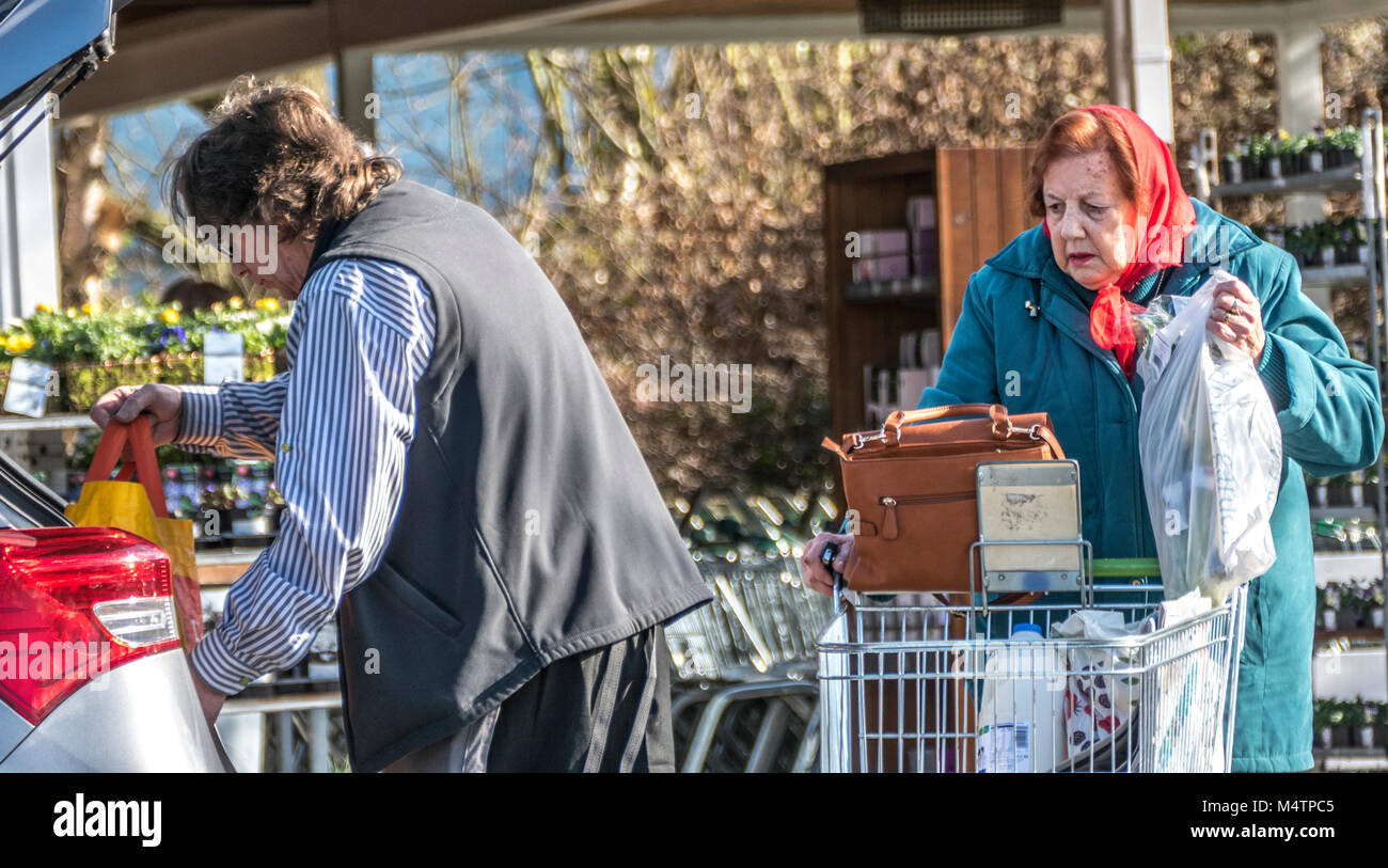 Male Waitrose supermarket employee, helping an old / elderly woman with ...
