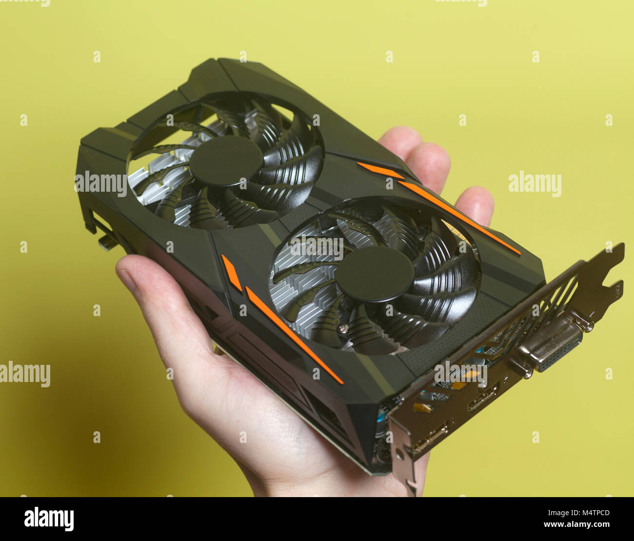 Graphic video card holding hand on yellow background Stock Photo - Alamy