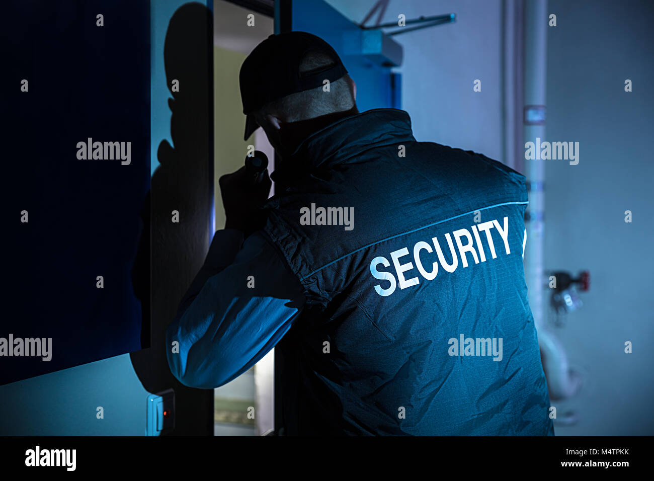 Rear View Of A Male Security Officer In Uniform Using Flashlight Stock ...