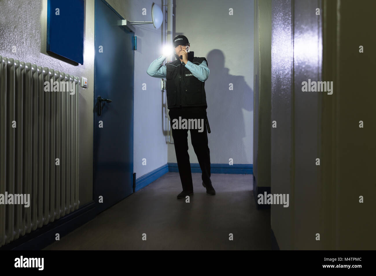 Male Security Guard With Flashlight Standing In Corridor Of The ...