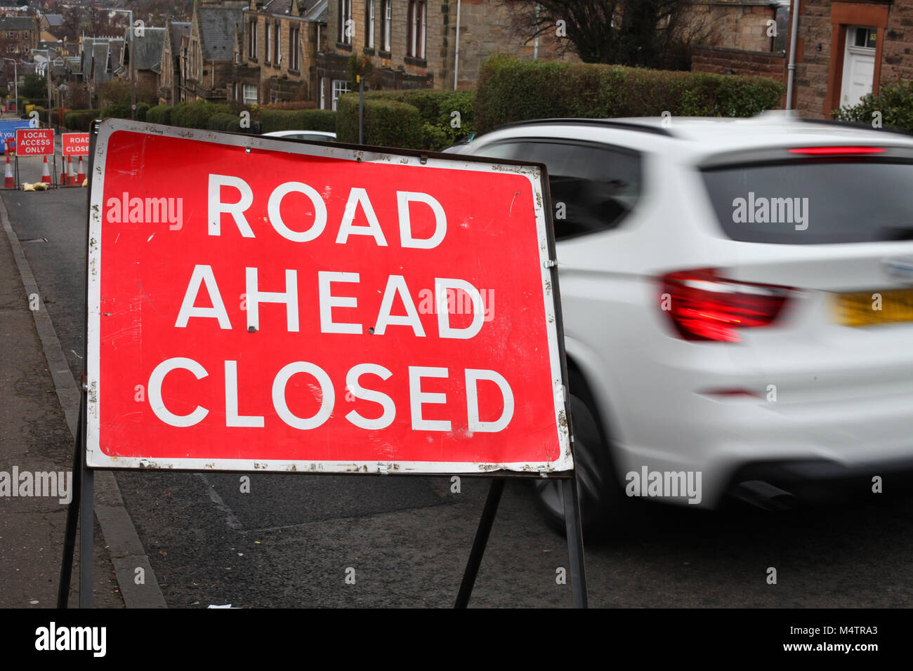 A car passes a road ahead closed sign to gain access to the local area ...