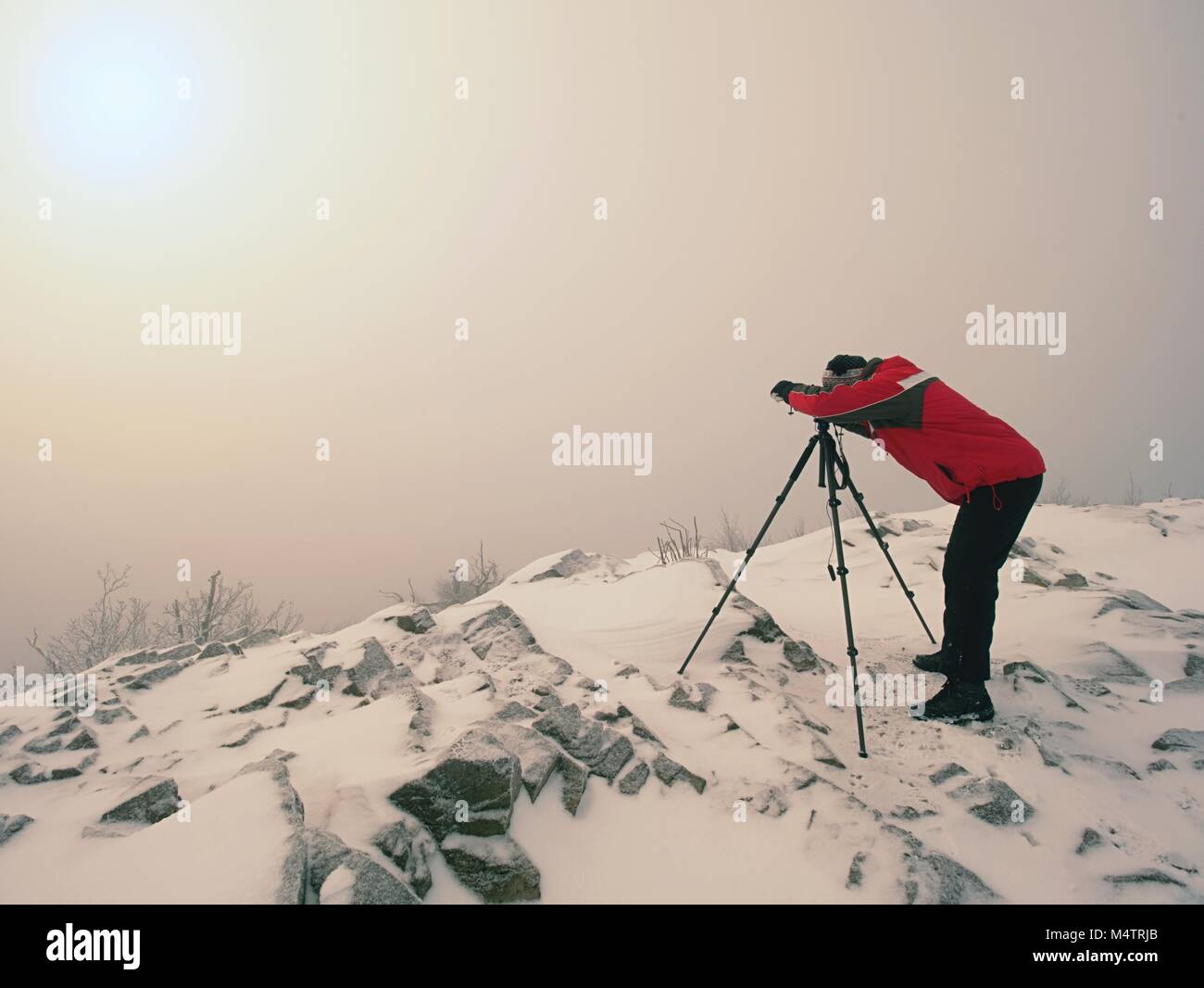 Travel photographer doing pictures in ancient stones on snowy peak of ...