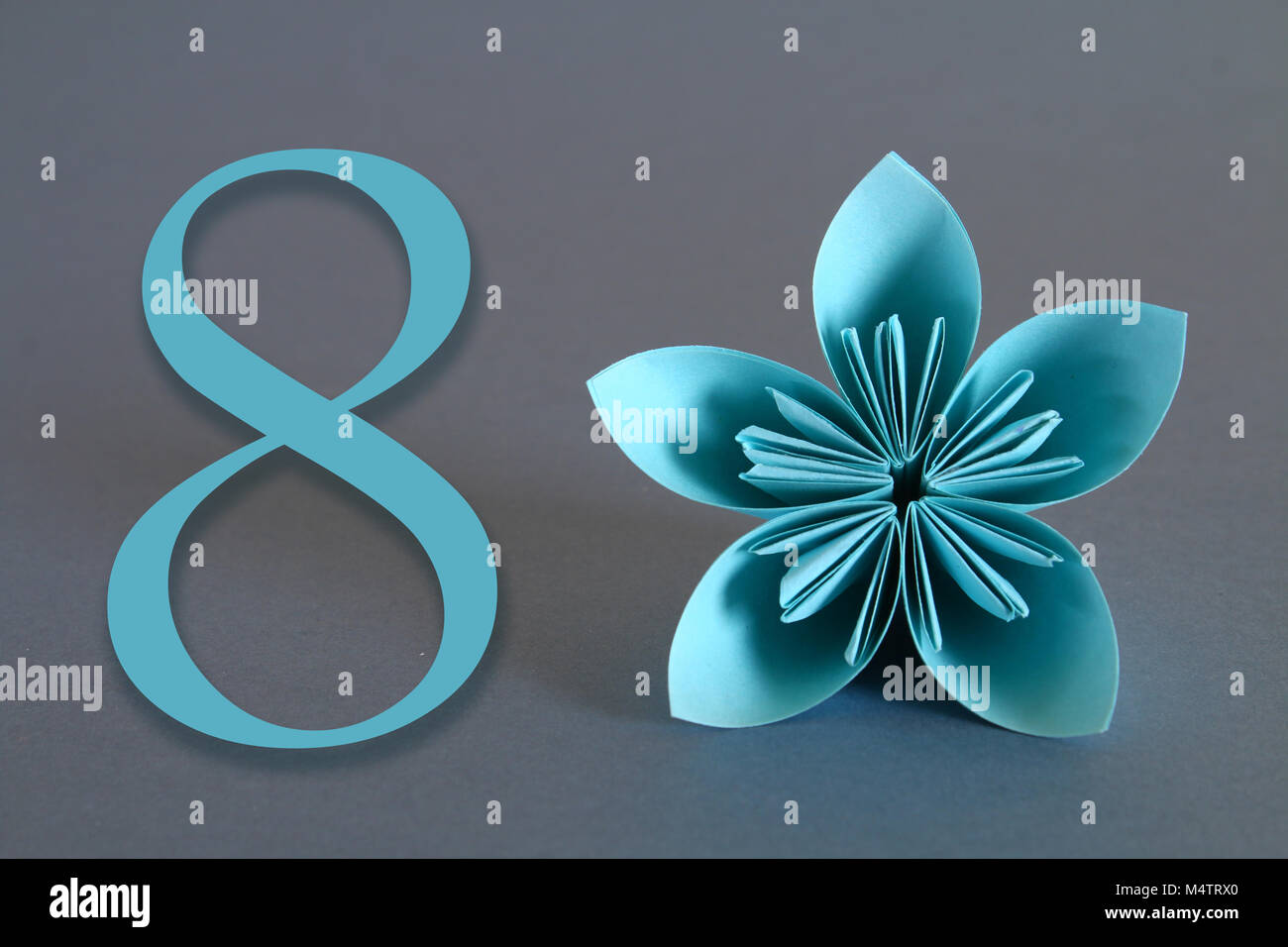 Paper flower from origami with the number eight on a gray background ...