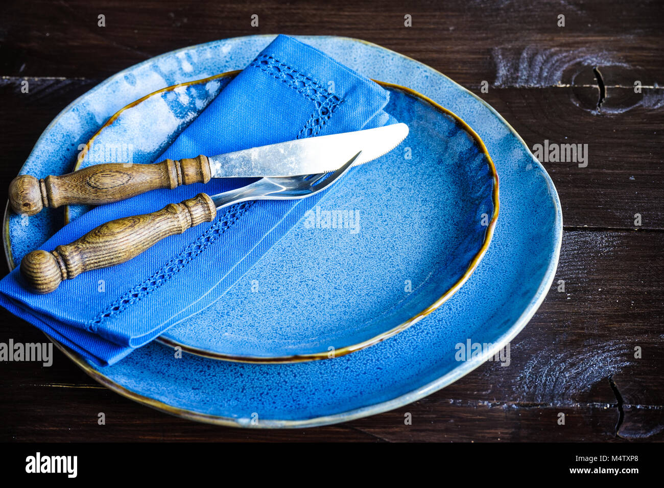 Rustic table setting with ceramic plates, napkin and silverware on dark ...