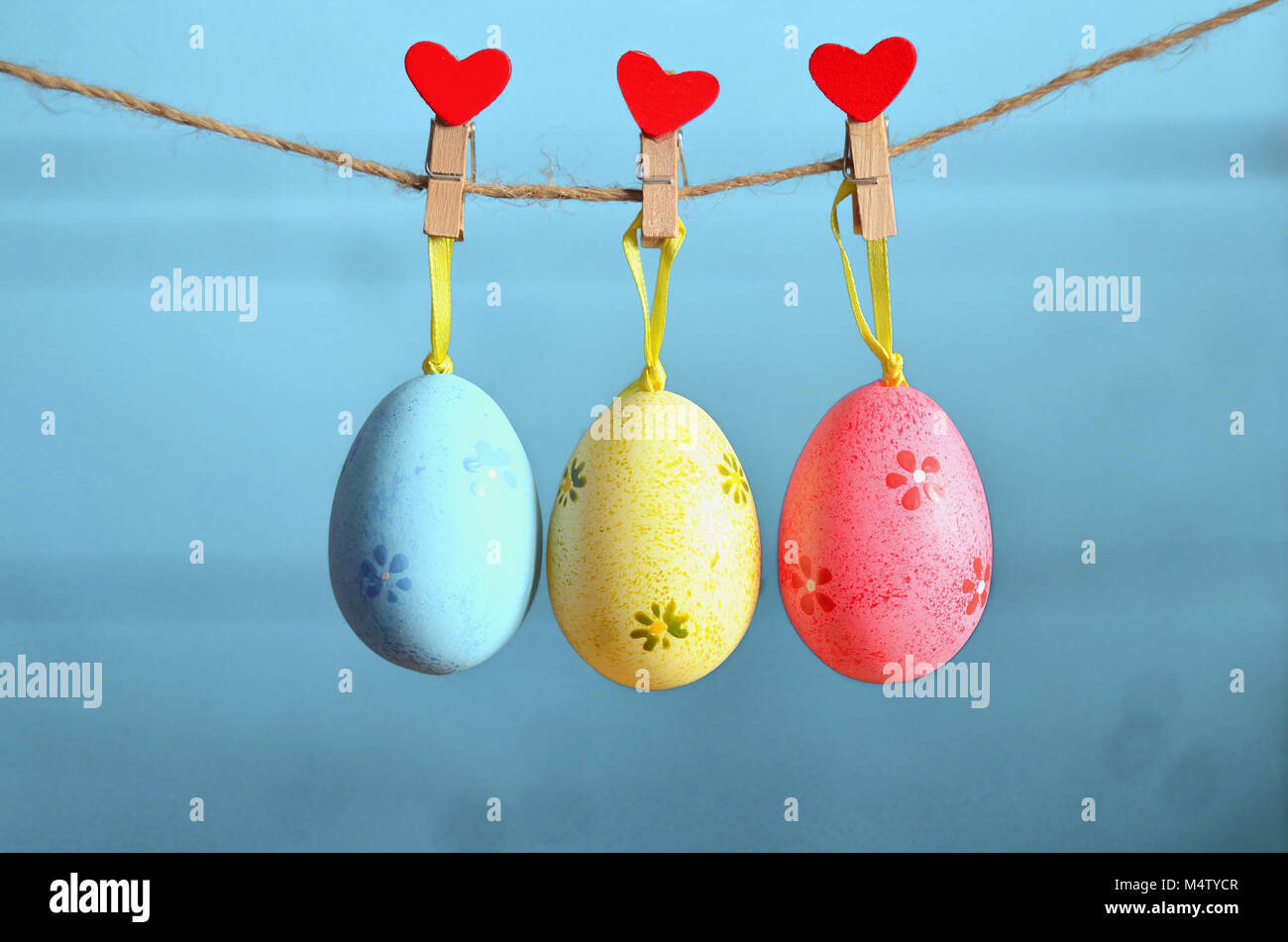 Easter eggs hanging on rope on blue wooden background Stock Photo - Alamy