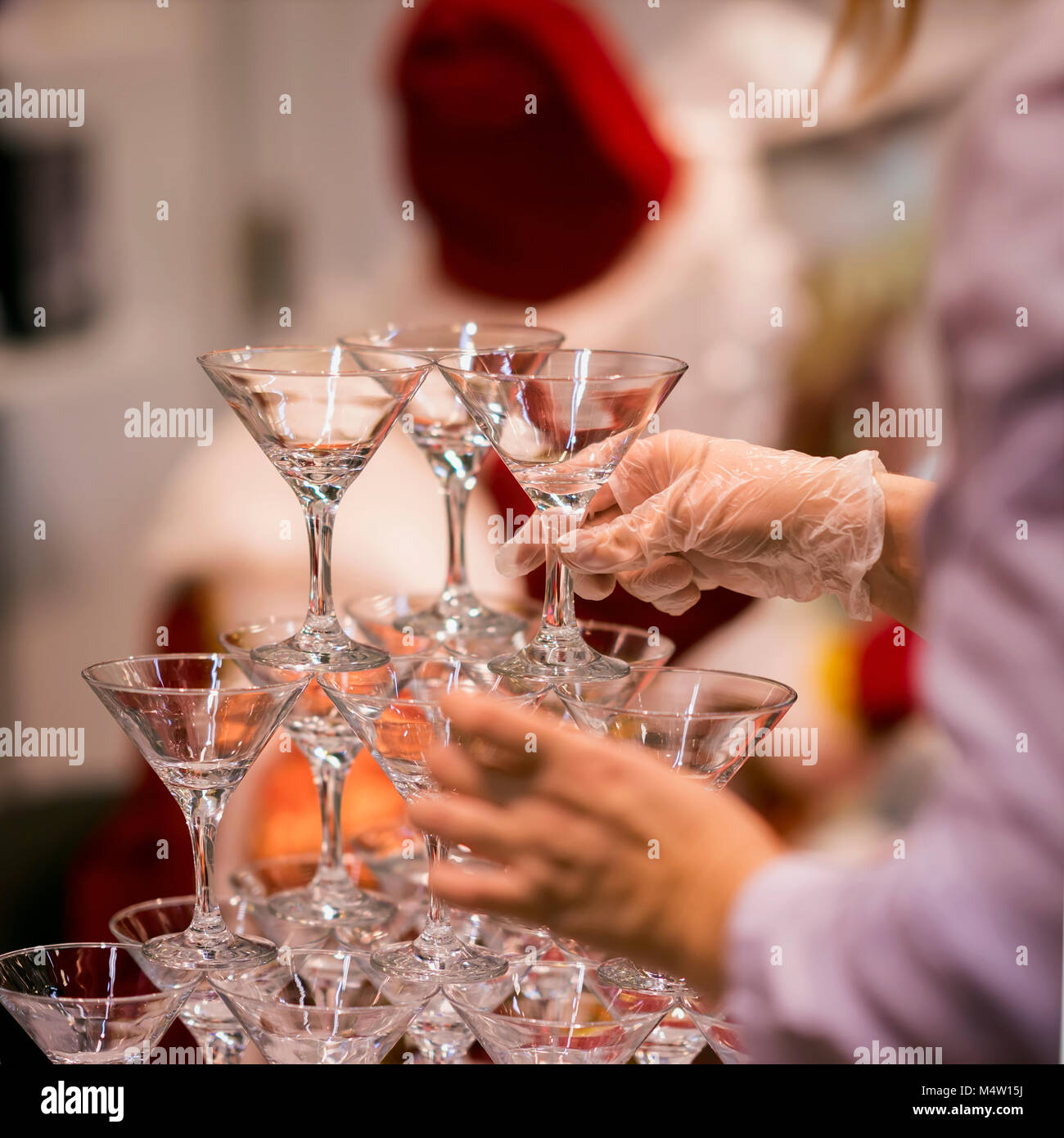 Hands of waiter in rubber gloves making a pyramid out of glasses for ...