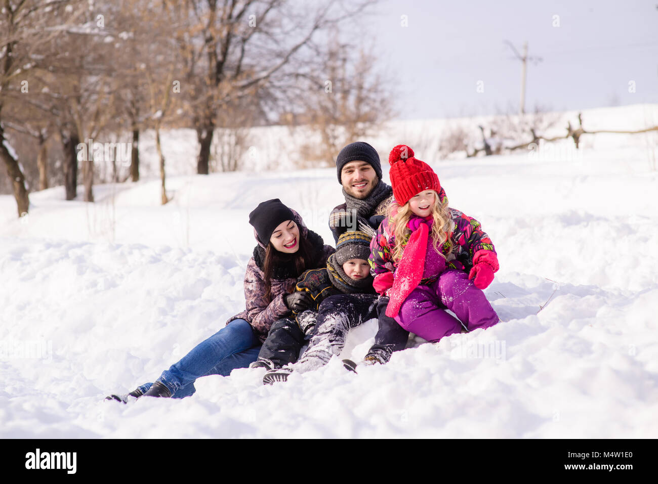 Happy family of four sitting in snow forest Stock Photo - Alamy