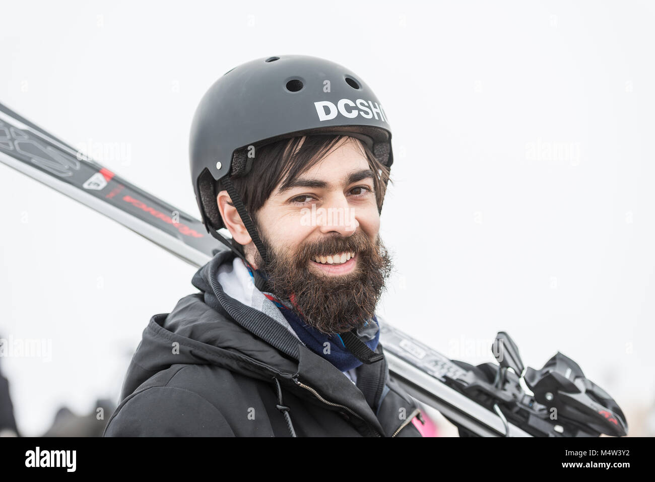 A young man with a beard and a black helmet ready to ski at the Sierra ...