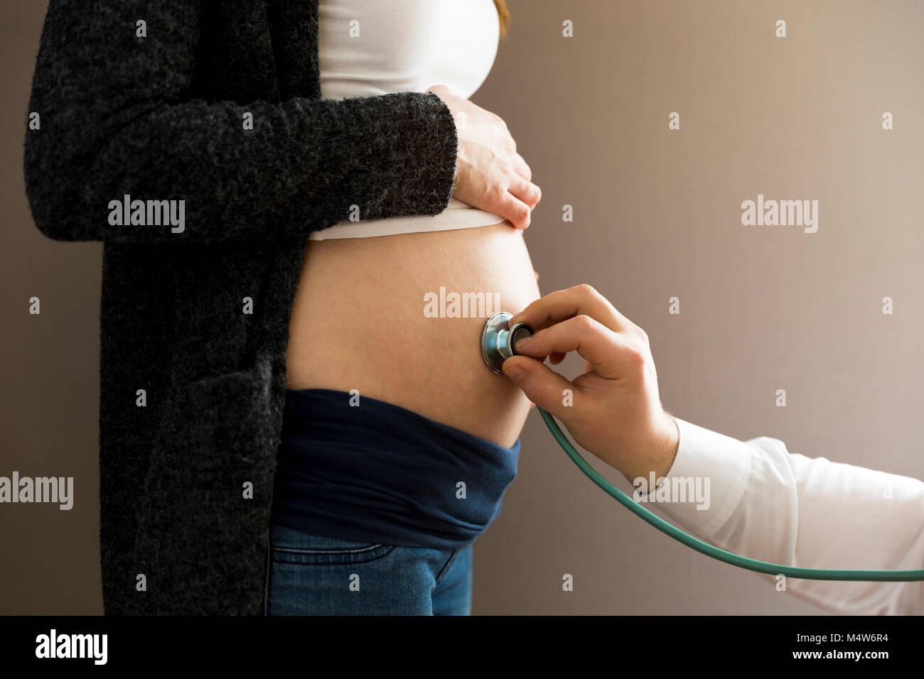 Pregnant woman examining by a doctor with a stethoscope Stock Photo - Alamy