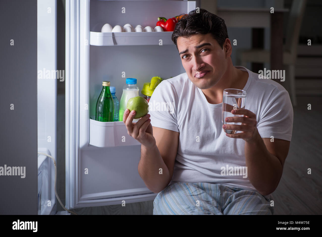 Man at the fridge eating at night Stock Photo - Alamy
