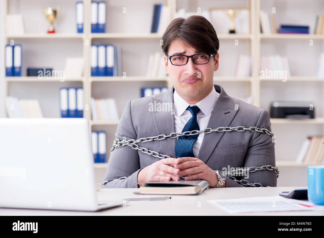 Businessman tied with chains to his work Stock Photo - Alamy