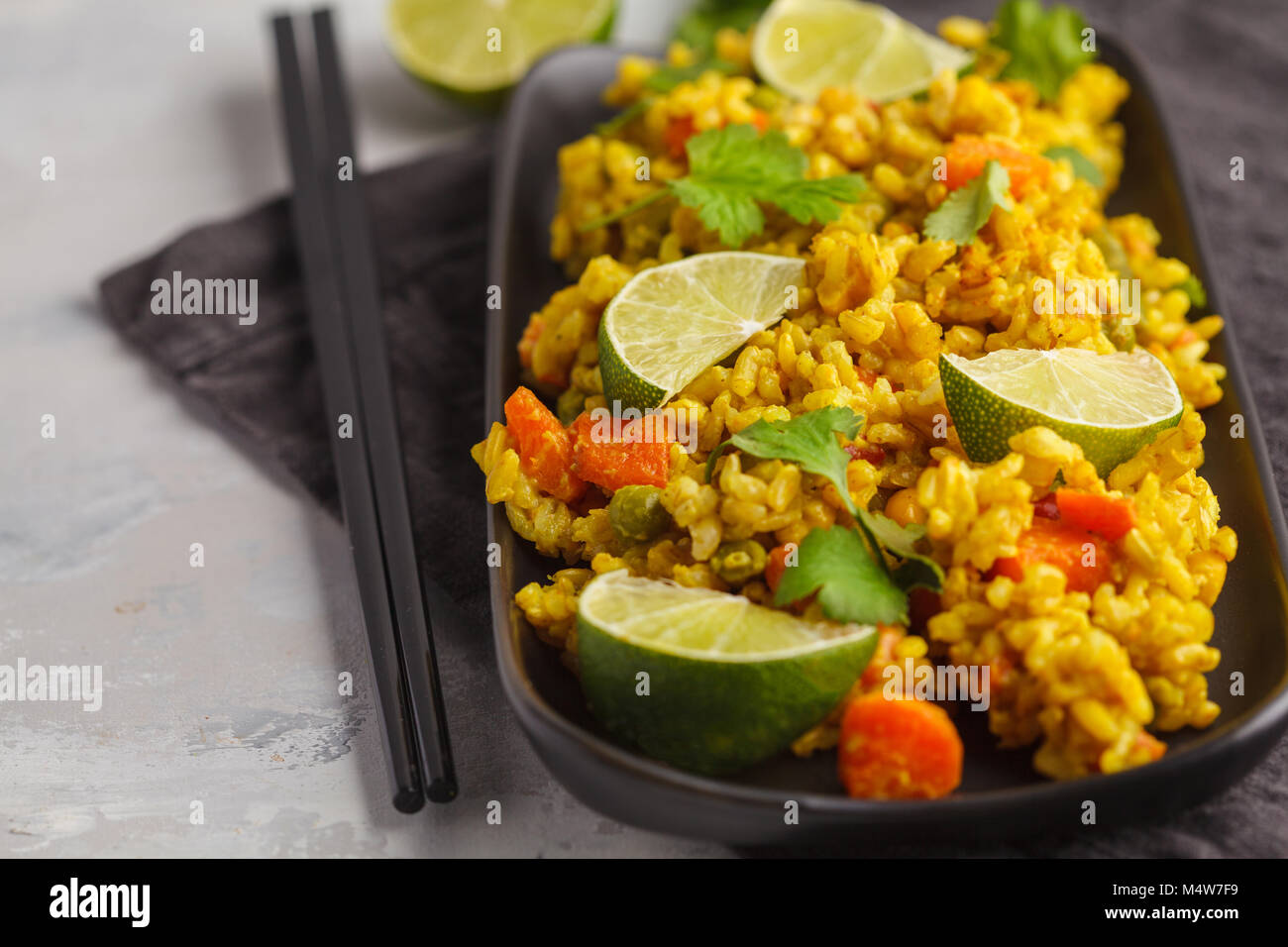 Vegetarian curry rice with vegetables in a black plate. Gray background ...