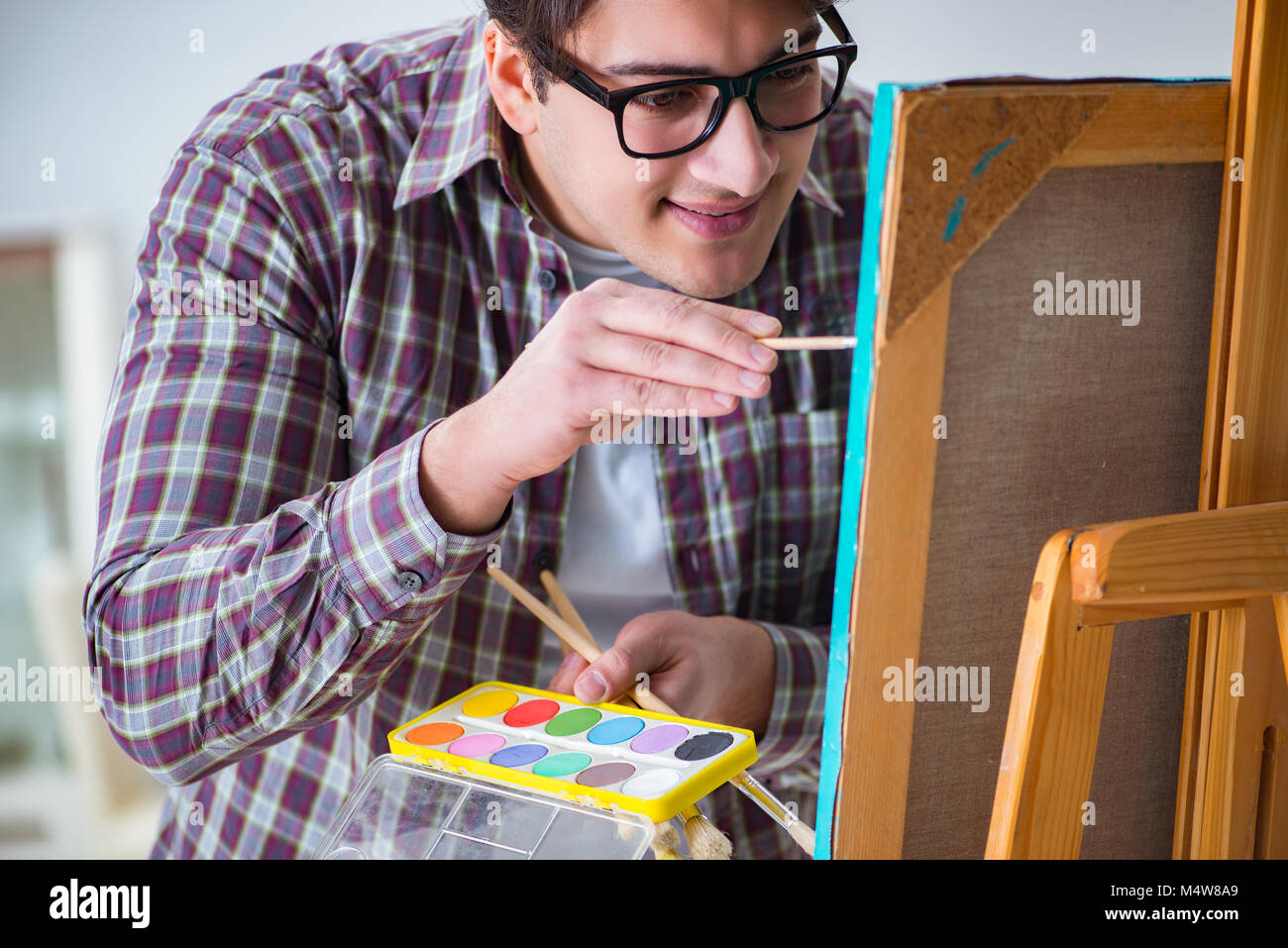Young male artist drawing pictures in bright studio Stock Photo - Alamy