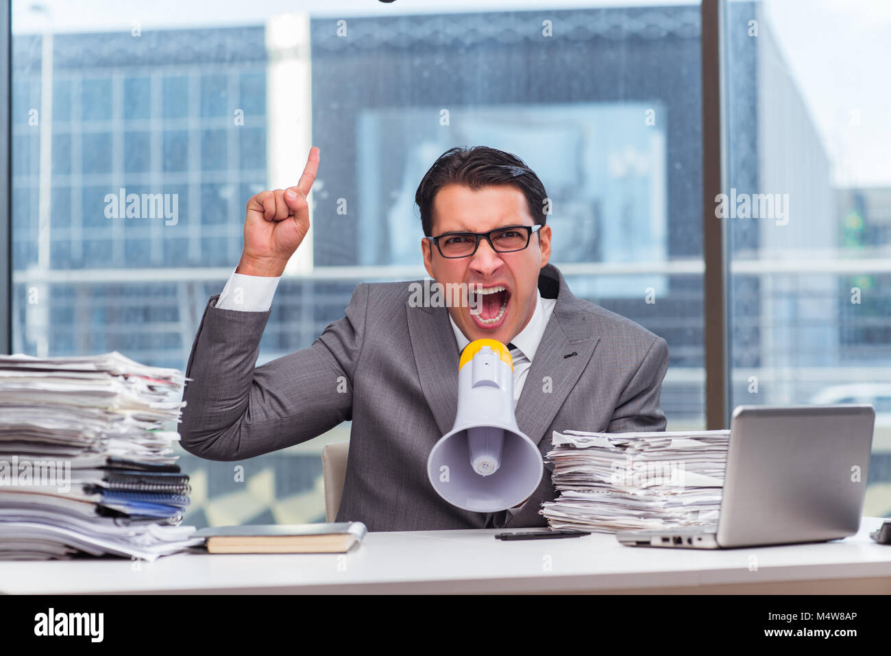 Angry businessman with loudspeaker in the office Stock Photo - Alamy