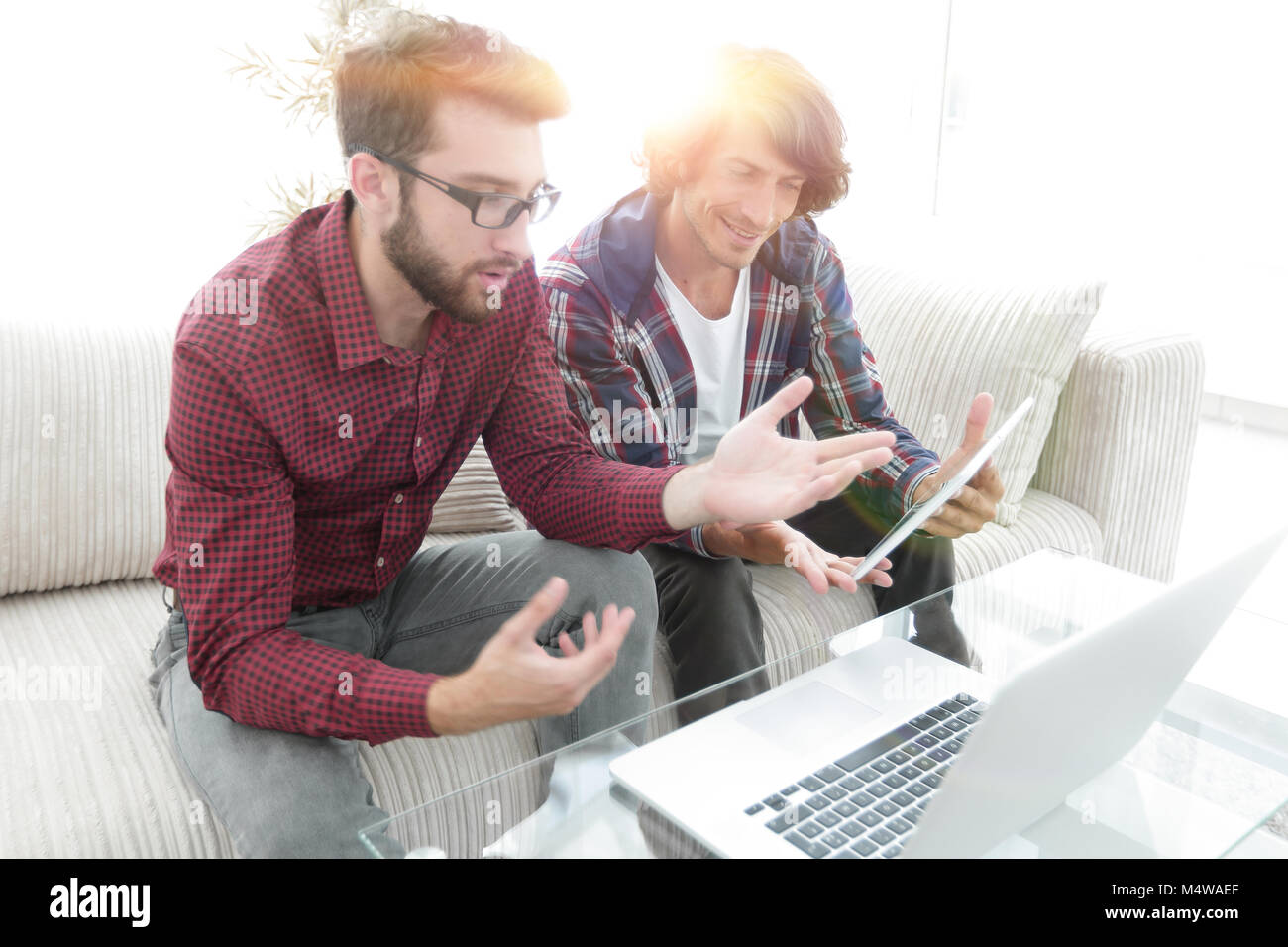 two guys sitting on the couch and looking at the laptop screen Stock ...
