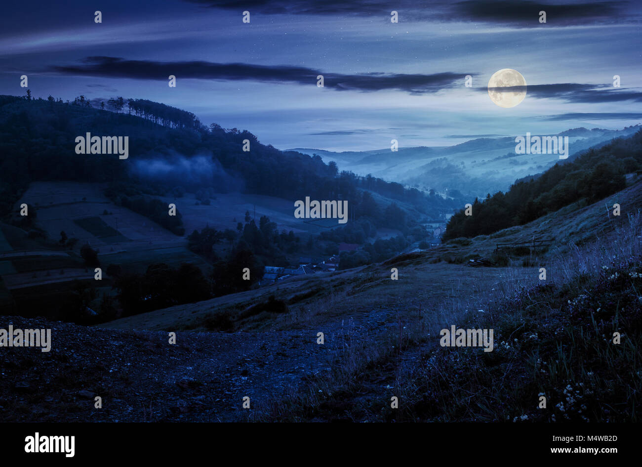 rural valley with forested hills at night in full moon light. beautiful ...