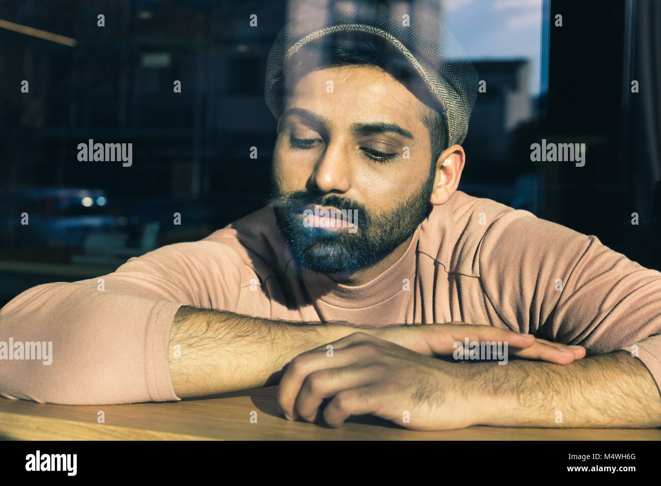 Portrait of a handsome Indian man posing behind a reflecting glass ...
