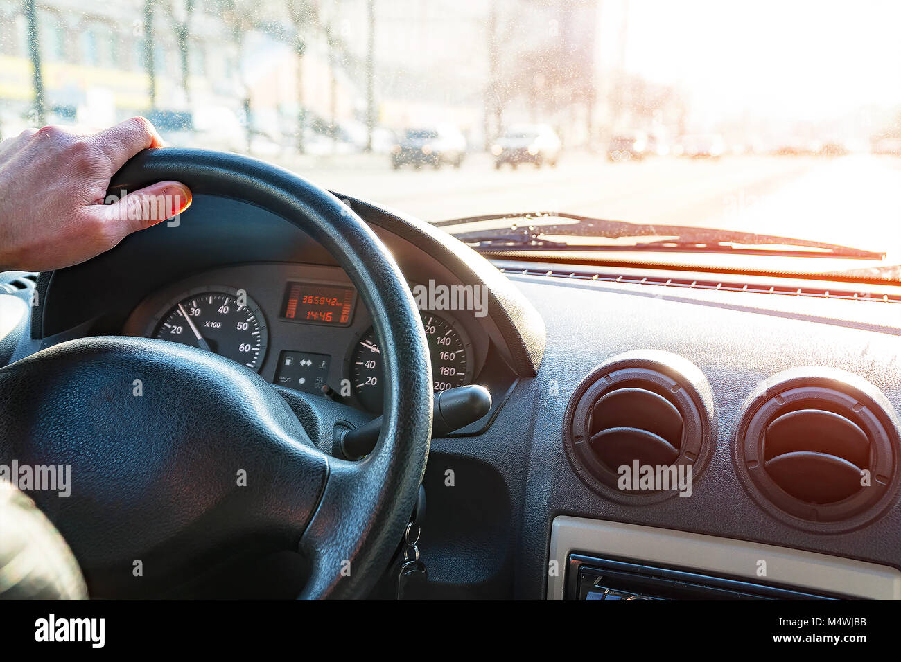 Hands on the steering wheel. View of the road in the city through the ...