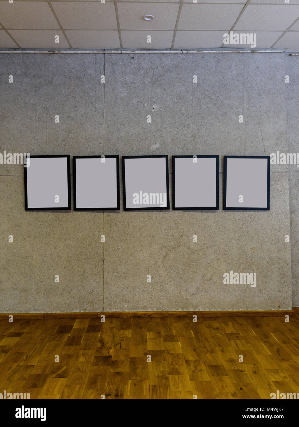 exhibition hall with concrete walls and black framed empty picture ...