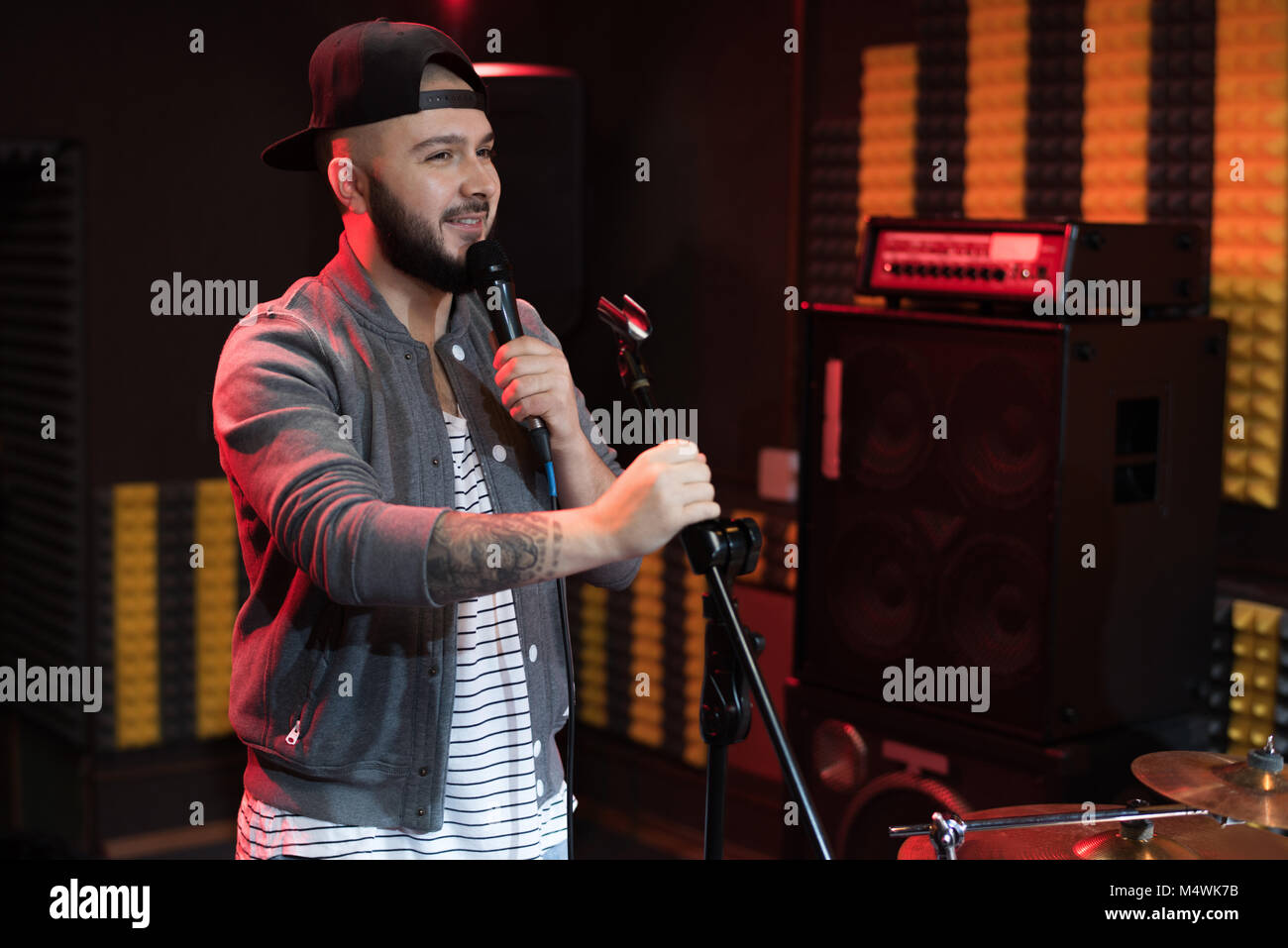Portrait of young hip-hop musician performing in dim recording studio ...