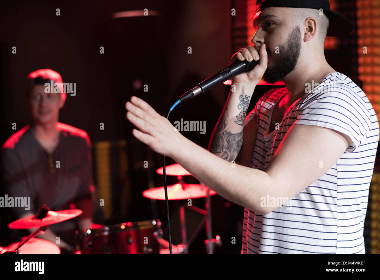 Side view portrait of tattooed hip-hop singer with his music band ...