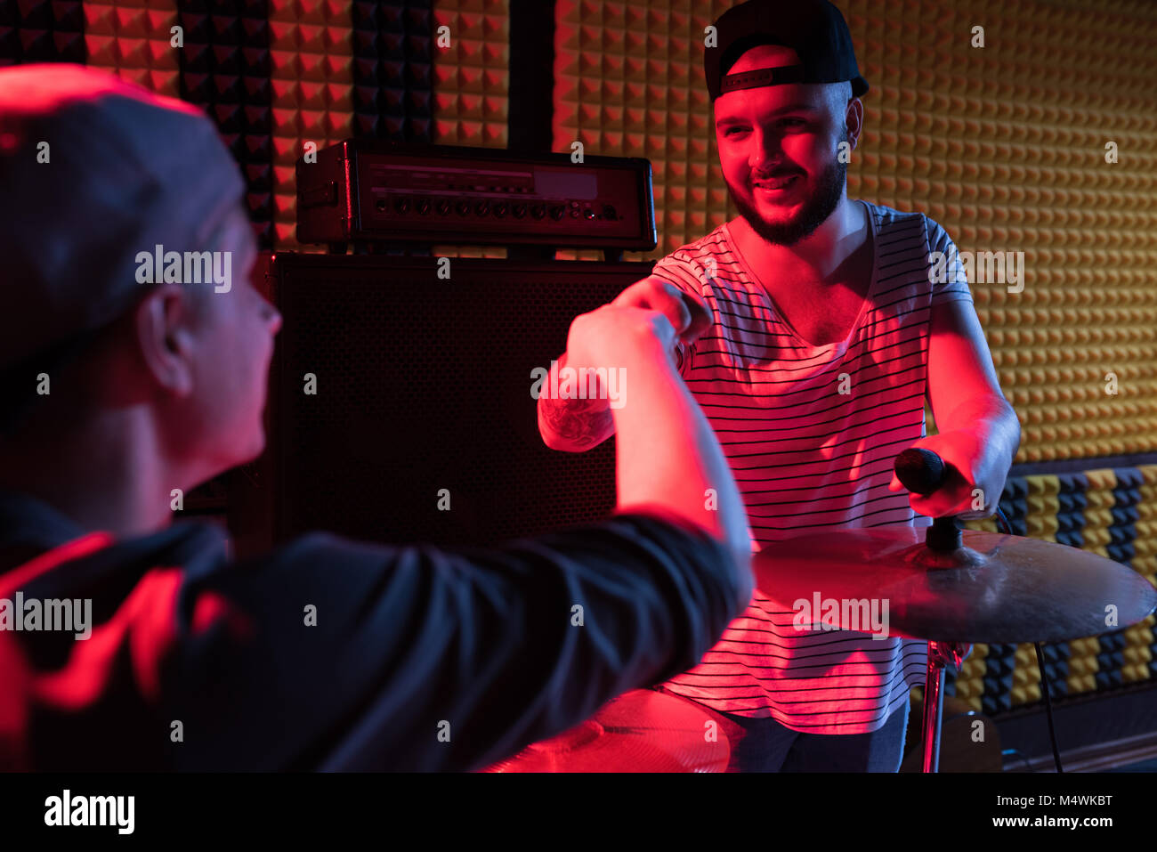 Portrait of tattooed modern singer fitstbumping drummer while ...