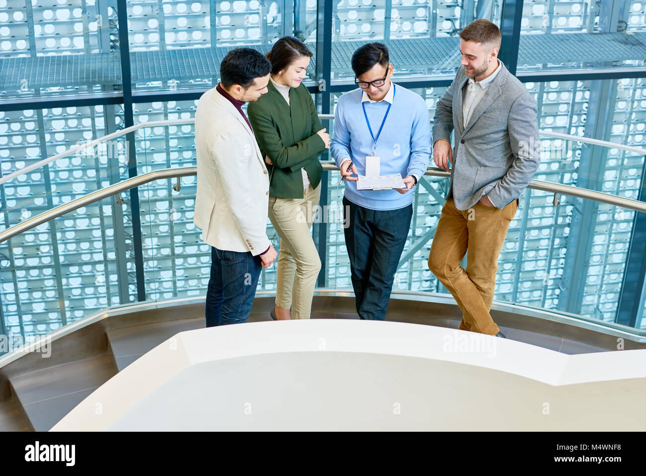 Portrait of four young business people chatting while standing at ...