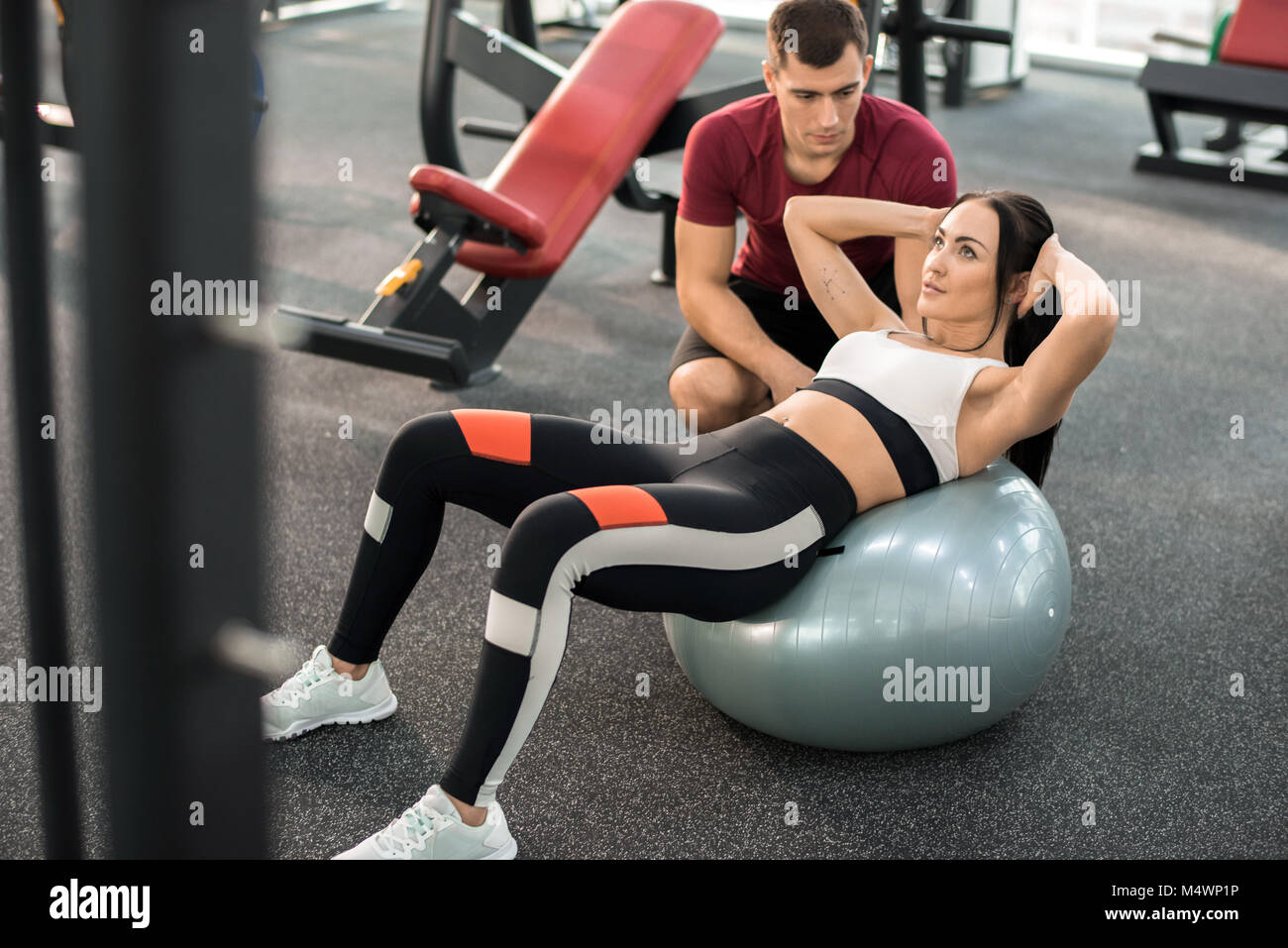 High angle portrait of muscular coach helping young woman doing ...