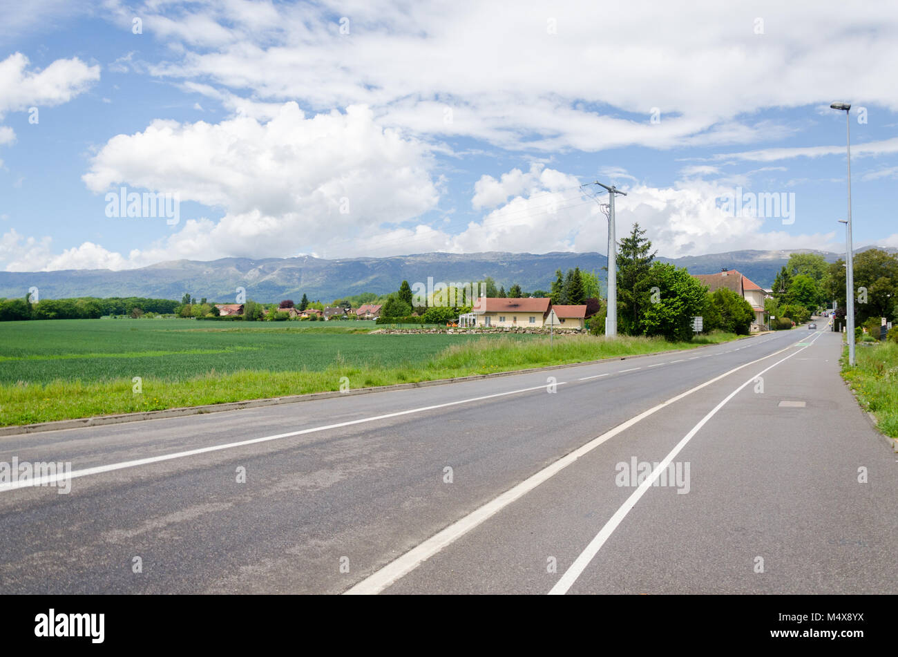 French countryside road passing through vast grassland under cloudy ...