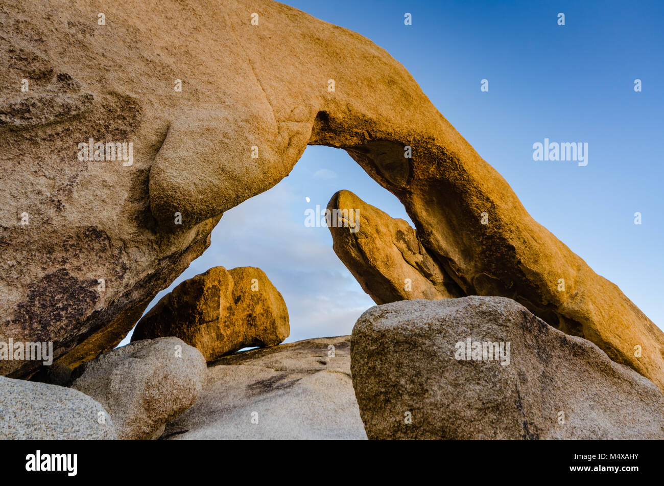 Twilight view of half moon through arch rock formation at Joshua Tree ...