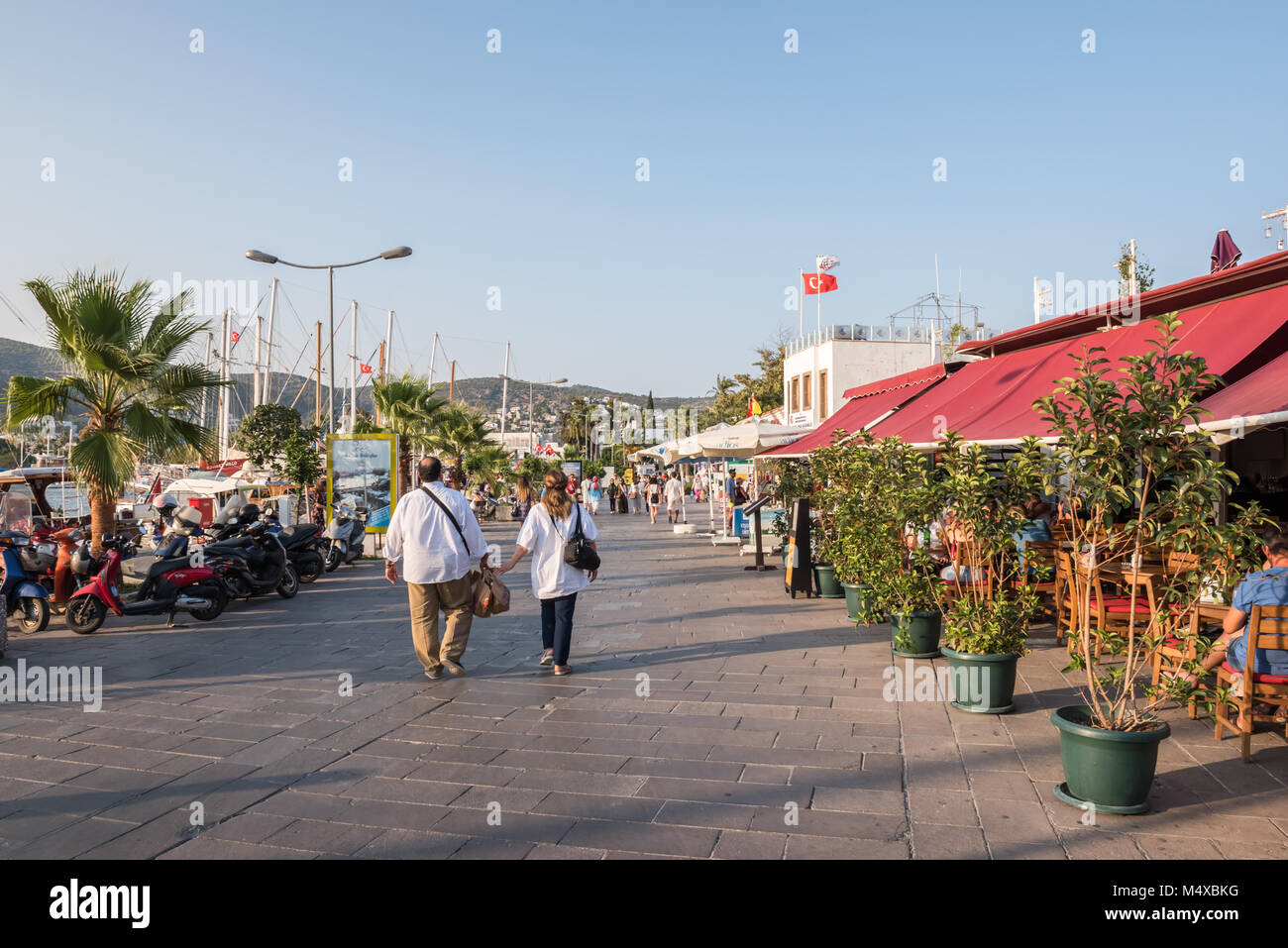 Unidentified people walk along shore in Bodrum with blue sky.Bodrum ...