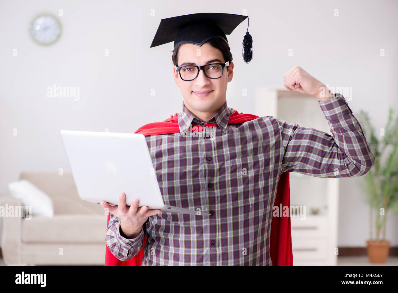 Super hero student wearing mortarboard and holding a laptop Stock Photo ...