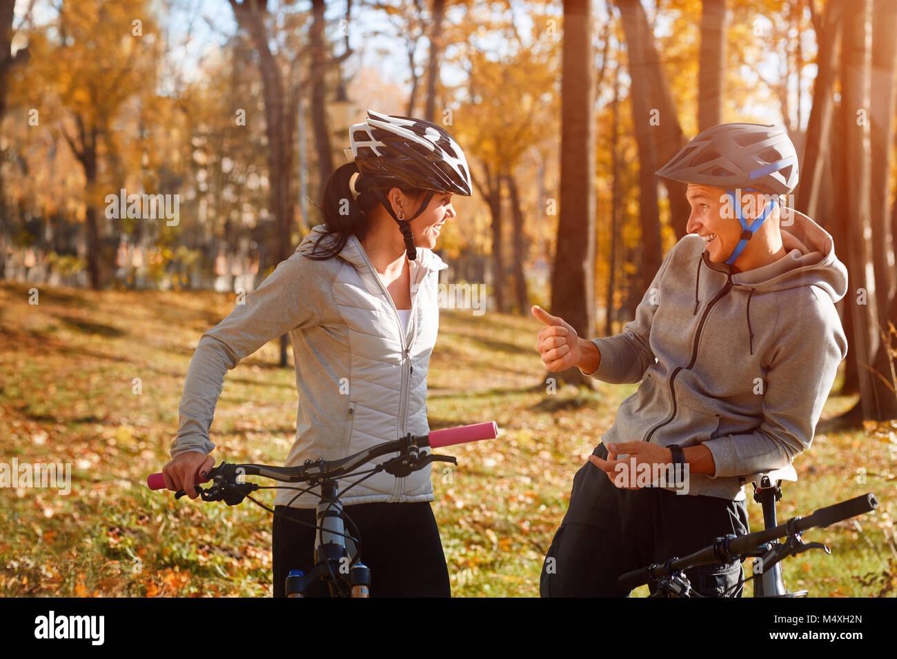 Happy young couple having fun riding a bicycle on sunny autumn day in ...