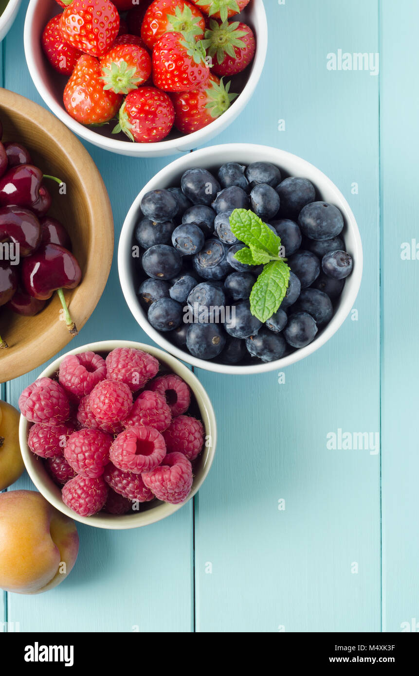 Overhead shot of five separated fruit types on light aqua blue painted ...