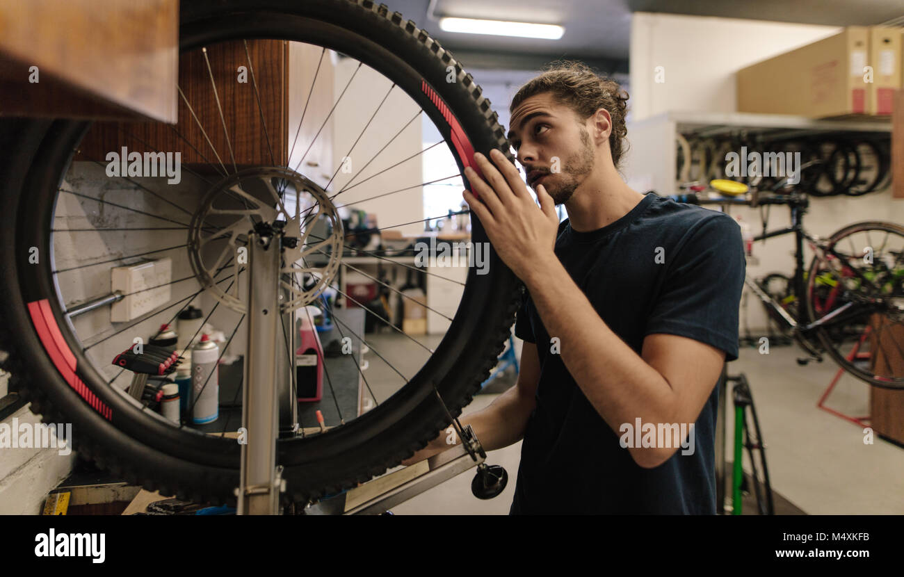 Man working on a bicycle wheel in a repair shop. Worker fixing a ...