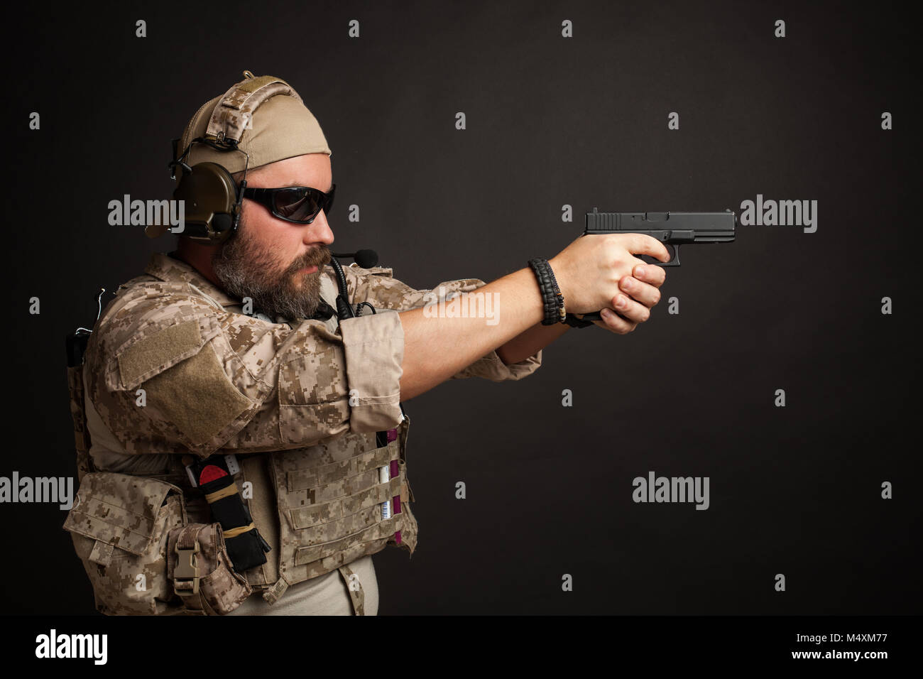 Brutal man in the military desert uniform and body armor standing in a ...